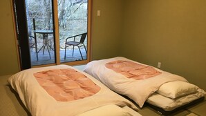 Duas camas de solteiro com roupa de cama branca e cor de pêssego, porta de correr de vidro que dá para área externa com uma cadeira.