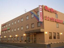 Um hotel com vários andares, entrada visível e placa com texto em japonês.
