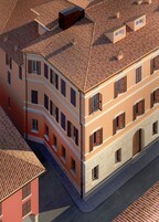 Um edifício de vários andares com telhado em telhas, várias janelas com persianas e uma entrada central com porta.