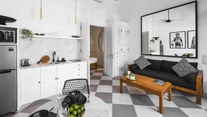 Uma sala de estar moderna com um sofá preto, uma mesa de centro de madeira e um chão xadrez.