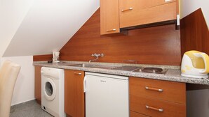 Uma cozinha compacta com máquina de lavar, lava-louças e cafeteira.