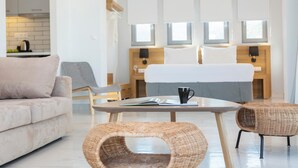 Quarto de hotel moderno com sofá, mesa de jantar e duas cadeiras de vime.