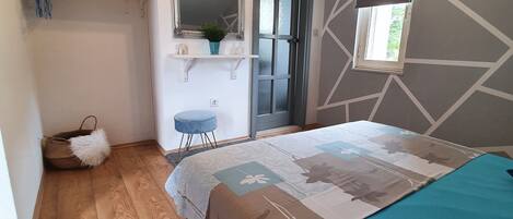 Quarto com cama, piso de madeira, espelho, janela e estantes embutidas.