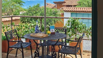 Um pátio com uma mesa redonda, quatro cadeiras e um grande guarda-sol.