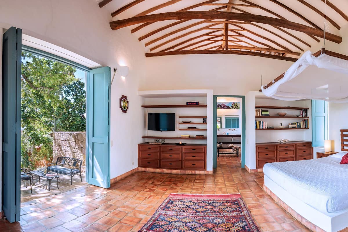 Quarto com cama, televisão, guarda-roupa, escrivaninha e cadeira.