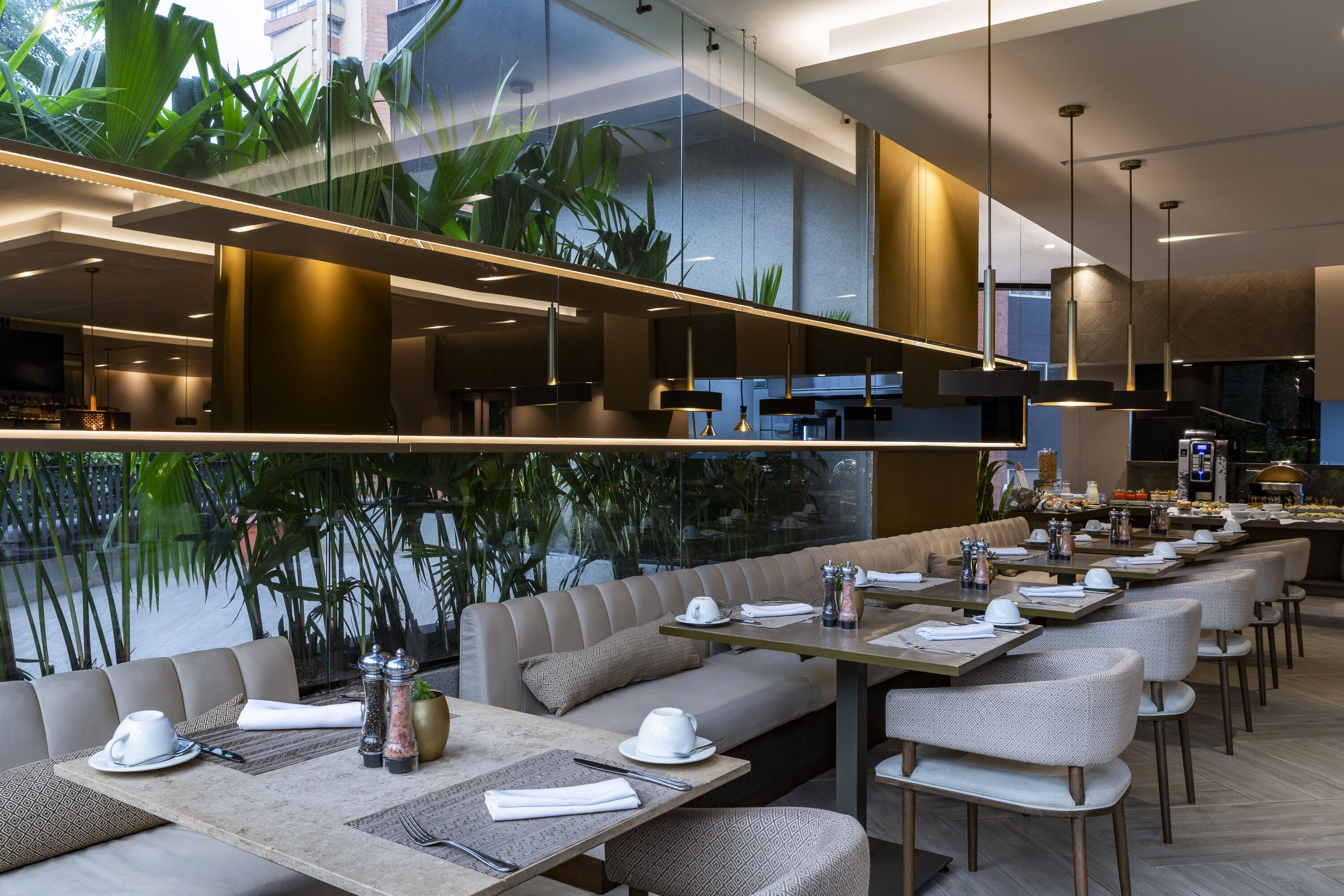 Um restaurante moderno com mesas altas, cabines, amplas janelas e plantas em interior.