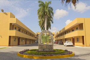 Hotel com um pátio central, apresentando uma palmeira e um arco de pedra.