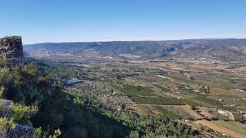 Vista panorâmica de um vale com campos em socalcos, uma pequena massa de água e um afloramento rochoso.