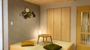 Um quarto com uma cama, uma pequena mesa redonda e um guarda-roupa.