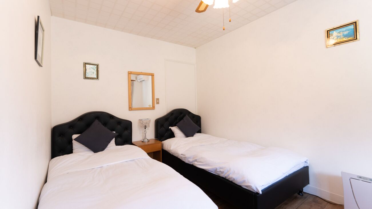 Quarto com duas camas, mesa de cabeceira, espelho e quadro pendurado na parede.