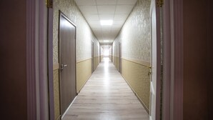 Um corredor comprido e estreito, com paredes estampadas e portas em ambos os lados.