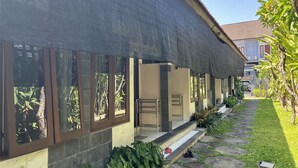 Um edifício moderno com grandes janelas, um alpendre coberto e um caminho de pedra que leva à entrada.