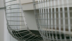 Primeiro plano de uma cadeira com estrutura de metal, assento e encosto pretos.