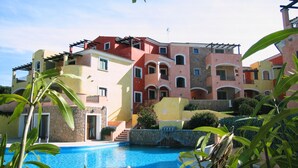 Um edifício com vários andares e uma piscina em primeiro plano.