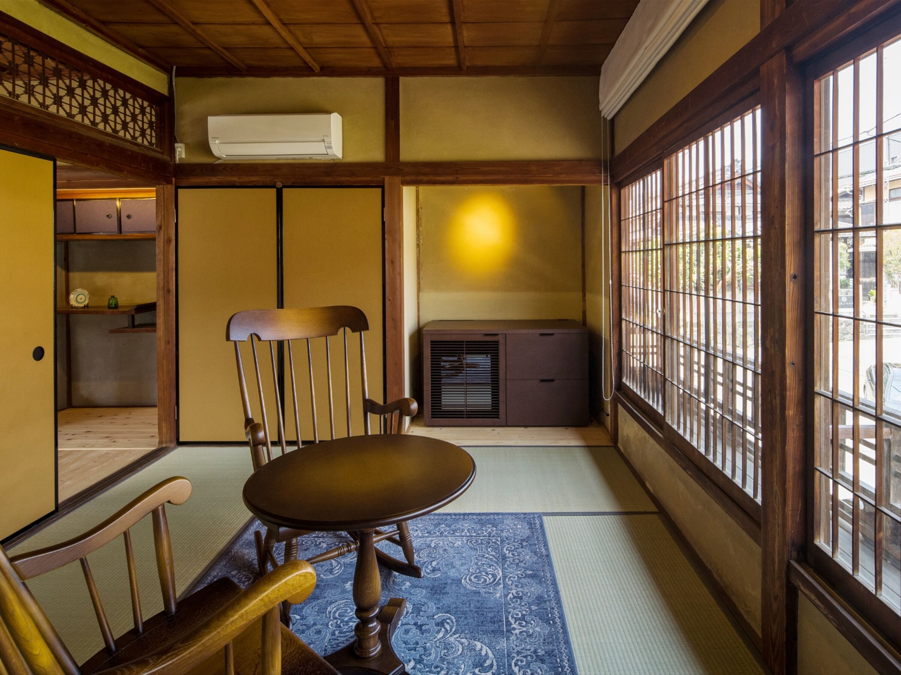 Um quarto japonês tradicional com tatames, uma mesa baixa e uma cadeira.