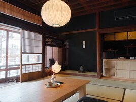 Um quarto japonês tradicional com tatames, uma mesa de madeira, um lanterna de papel pendurada e portas shoji deslizantes.