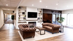 Uma sala de estar moderna com lareira, sofás de couro, televisão de tela plana e estantes.