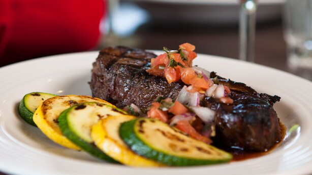 Prato de bife com legumes grelhados e um copo de vinho tinto.