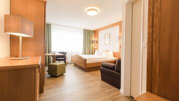 Quarto de hotel com cama, escrivaninha, sofá e luminária.