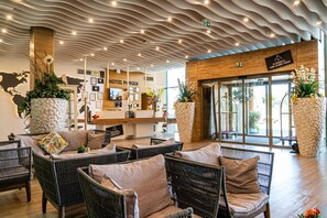 Um saguão de hotel com móveis de vime, um balcão de recepção e um design de teto moderno.