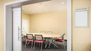 Uma sala de reuniões com uma mesa grande e seis cadeiras, uma porta e um aviso indicando a finalidade do espaço.