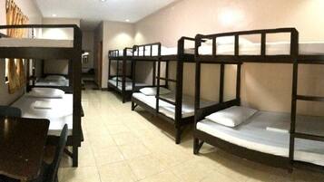 Quarto em dormitório com beliches, uma mesa e cadeiras.