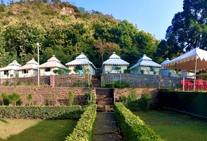Conjunto de edifícios com telhados brancos, paredes de pedra, escadaria de pedra e um jardim bem cuidado.