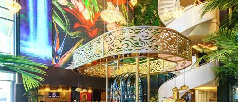 Um lobby moderno com uma recepção central, uma escada em espiral e luminárias pendentes.