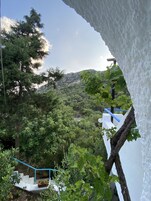 Vista de uma encosta verdejante e exuberante com um edifício branco, balaústres azuis e uma escadaria descendo.