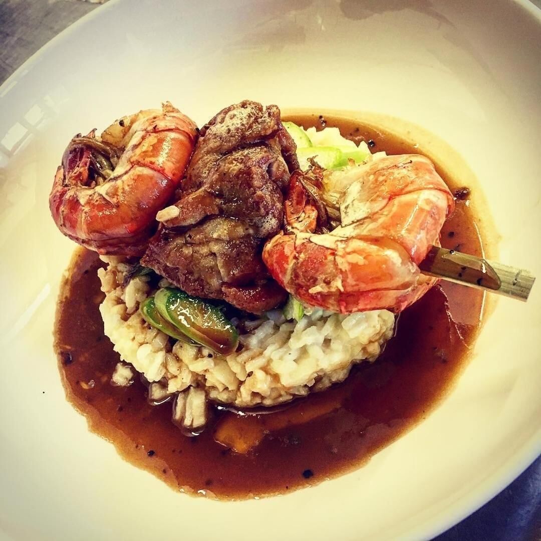 Um prato de comida com camarão, carne e arroz.