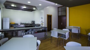 Cozinha moderna com ilha central, cadeiras brancas e uma parede com detalhes em amarelo.
