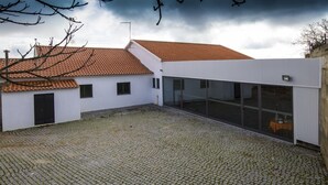 Um edifício com telhado telhado, pátio com chão de calçada e grandes janelas de vidro.