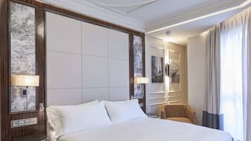 Quarto de hotel moderno com uma cama grande, uma luminária redonda no teto, uma mesinha de cabeceira e um espelho.