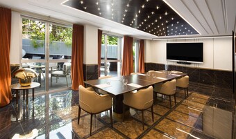 Uma sala de conferência com uma mesa comprida, seis cadeiras, uma TV de tela plana e um teto com luzes semelhantes a estrelas.