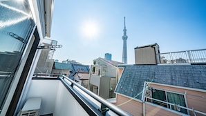 Terraço com vista para a Torre de Tóquio, grades de metal e um edifício com telhado inclinado.