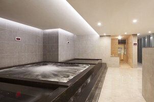 Uma área de spa moderna com hidromassagem e chuveiro separado.