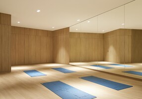Quarto com paredes de painel de madeira, um espelho grande e tapetes de yoga azuis no chão.