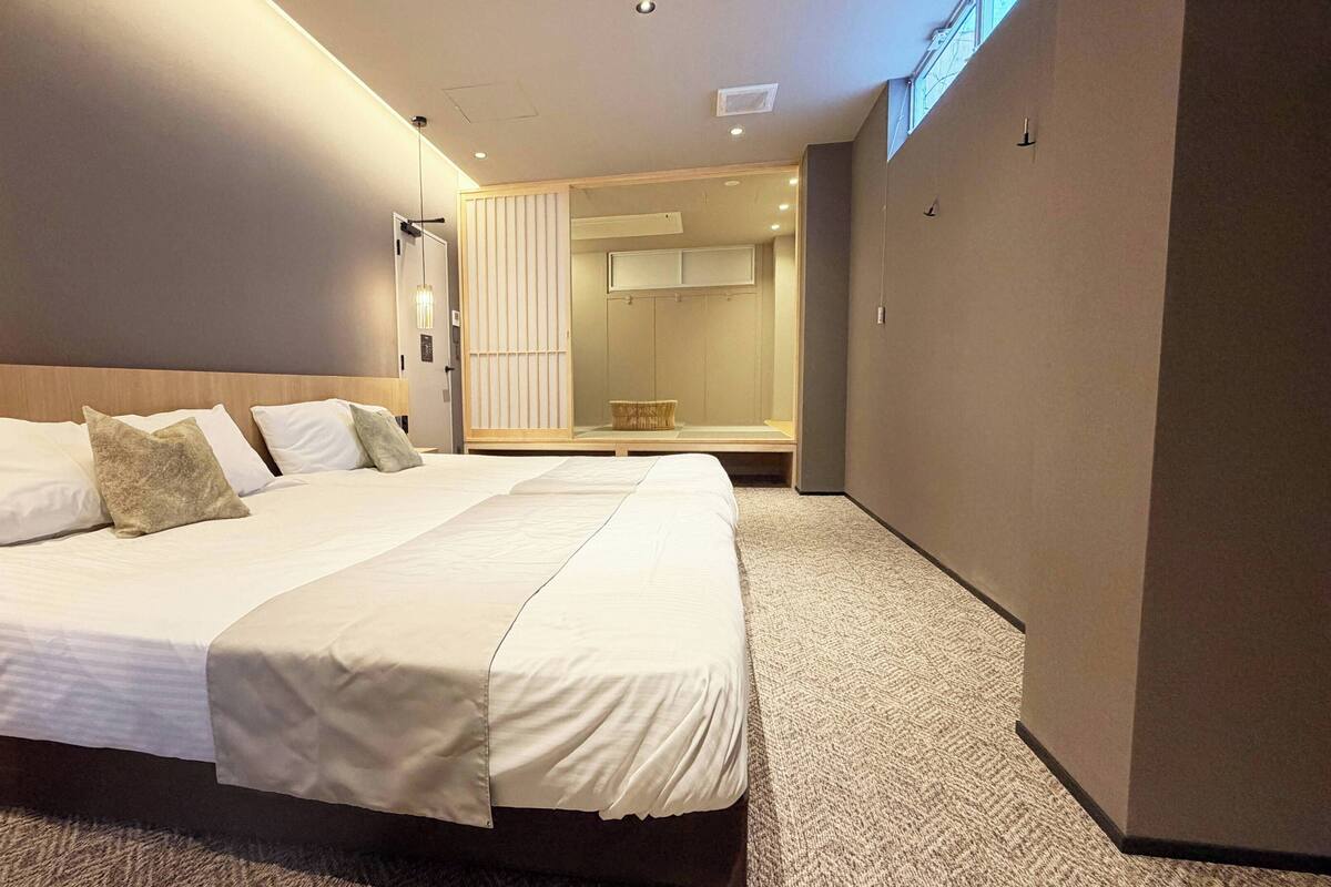 Quarto de hotel moderno com uma cama grande, um closet espaçoso e um espelho amplo.