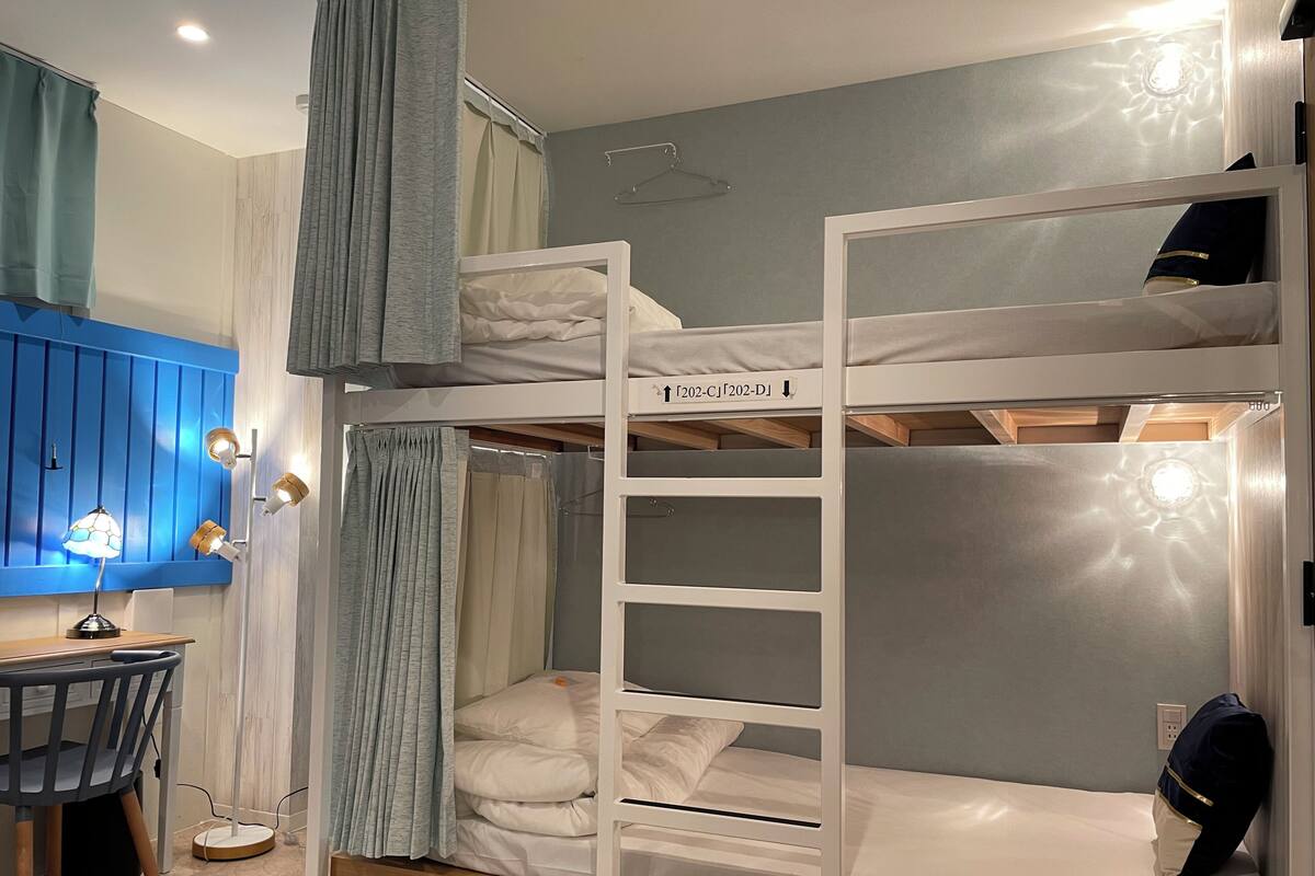 Quarto com beliche, uma escrivaninha, duas luminárias fixadas na parede e um lustre.