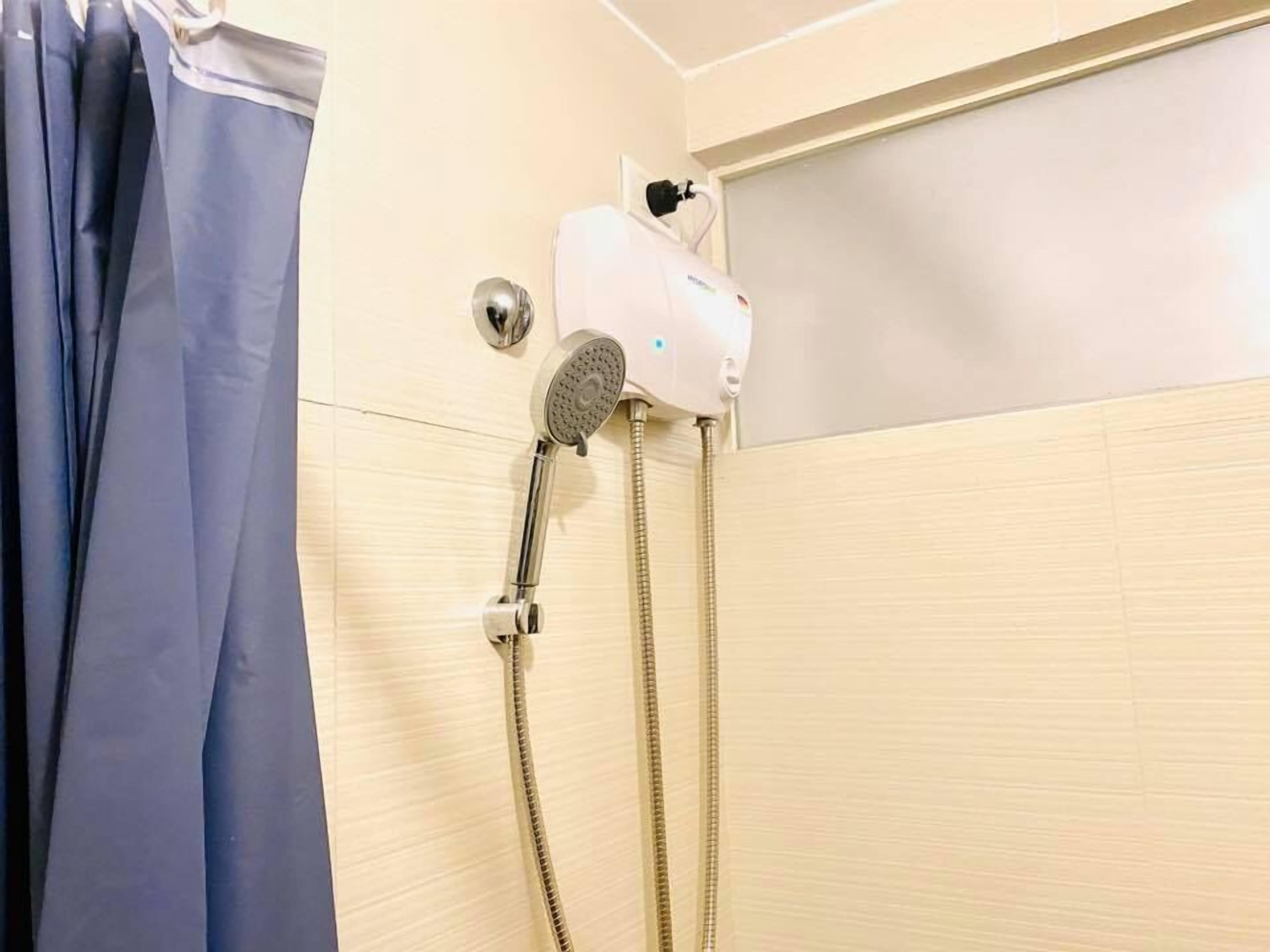 Casa de banho com chuveiro, porta-toalhas e aquecedor de parede.