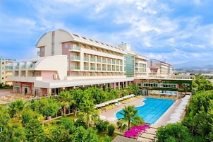 Um hotel com uma piscina grande, várias varandas e vegetação exuberante.