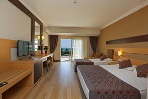 Quarto de hotel com duas camas, uma escrivaninha, televisão e varanda com vista.