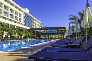 Um hotel com piscina, espreguiçadeiras e palmeiras.