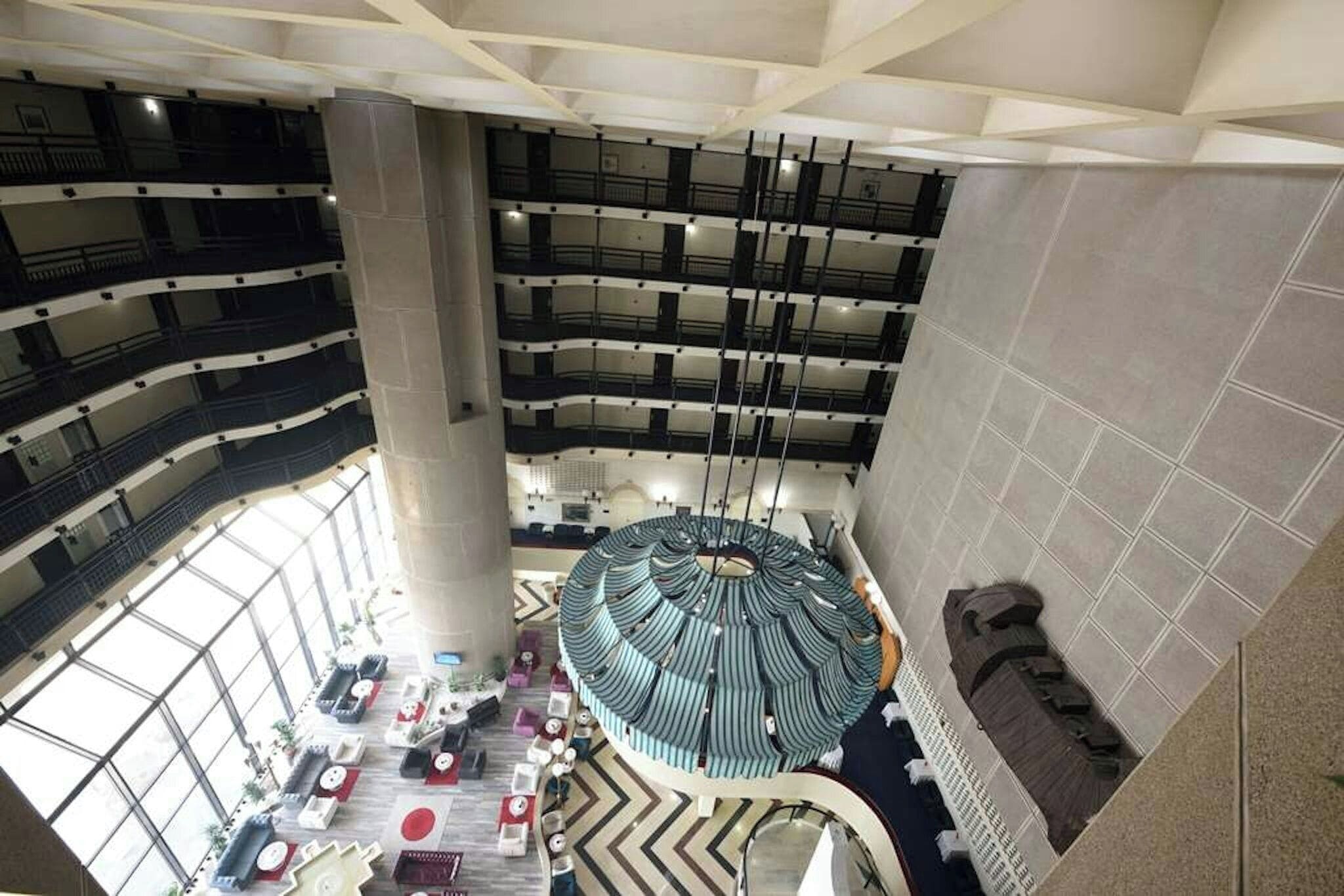 Um interior com vários níveis, um átrio central, diversos andares e uma área de estar circular.