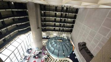 Um interior com vários níveis, um átrio central, diversos andares e uma área de estar circular.