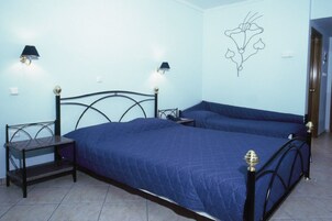 Quarto com duas camas, uma mesa de cabeceira e luminárias fixadas na parede.