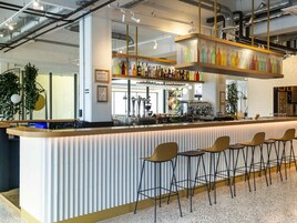 Uma área de bar moderna com balcão, banquetas e diversos tipos de garrafas.