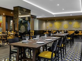 Um restaurante com mesas montadas para refeições, cadeiras e decoração na parede.