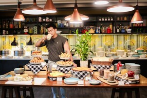 Disposição de buffet com diversos alimentos e uma pessoa servindo.
