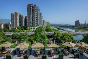 Um terraço no telhado com área de estar externa e vista para edifícios altos e um rio.
